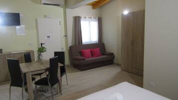 Um quarto com uma cama, uma mesa de jantar com cadeiras, um sofá e um guarda-roupa.