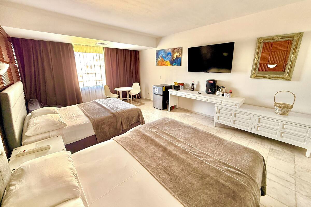 Quarto de hotel com duas camas, uma mesa de trabalho, televisão e minibar.