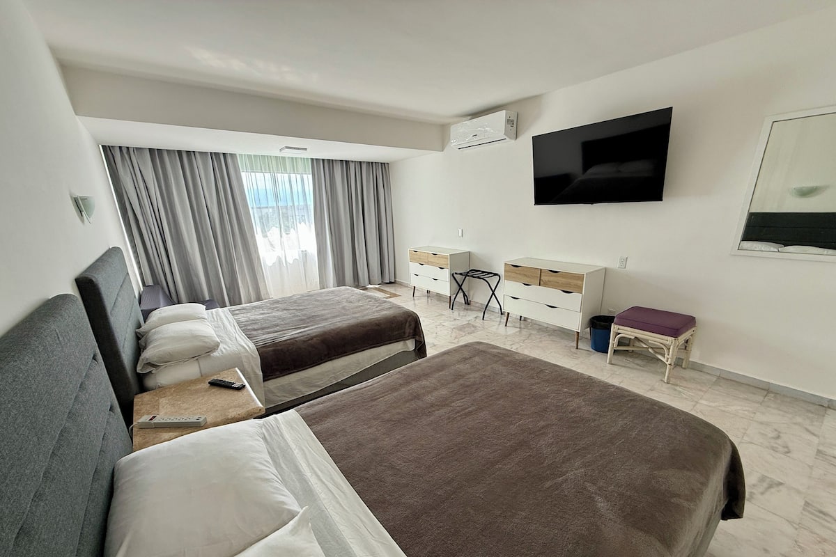 Quarto de hotel com duas camas, televisão, escrivaninha e cadeira.
