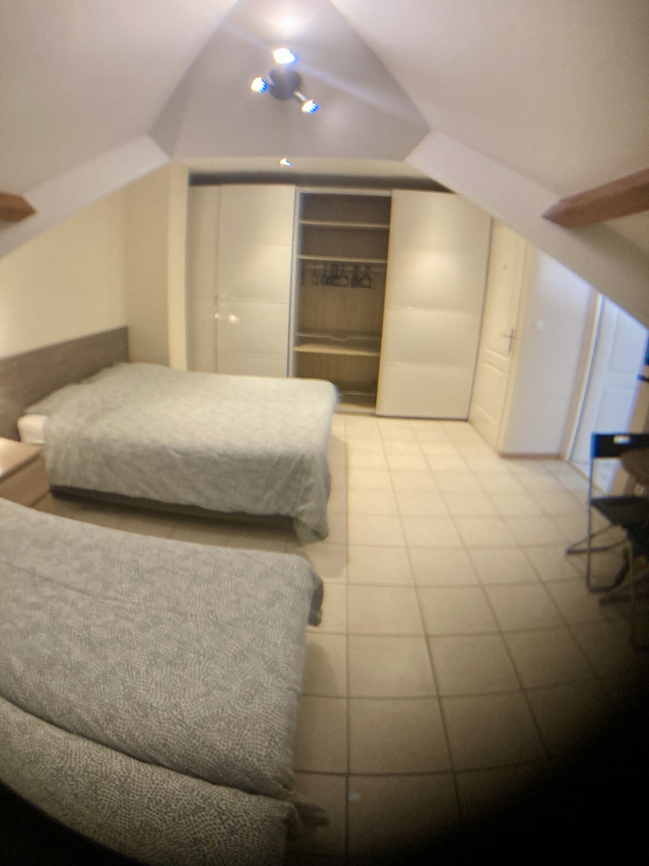 Quarto com duas camas, um guarda-roupa e um ventilador de teto.