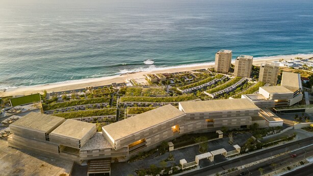 Vista aérea de uma área costeira com edifícios, uma praia e o oceano.