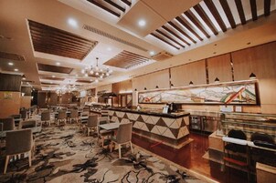 Um saguão de hotel com área de bar, disposição de assentos e carpete estampado.