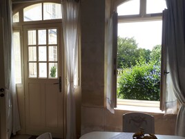 Um quarto com uma janela grande, uma porta e uma cadeira.