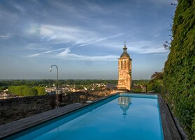 Piscina com uma parede de pedra e uma torre do relógio ao fundo.