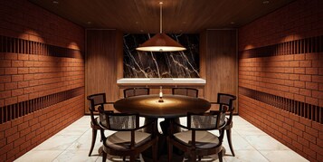 Uma mesa de jantar redonda com seis cadeiras, um painel de fundo de mármore e uma luminária pendente.