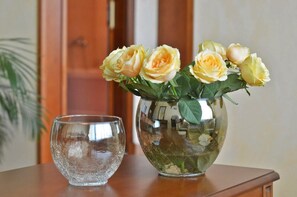 Um vaso de vidro com rosas amarelas sobre uma mesa de madeira.