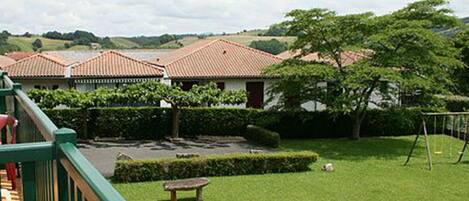 Um pátio com um parquinho, um banco e uma escultura de pedra.