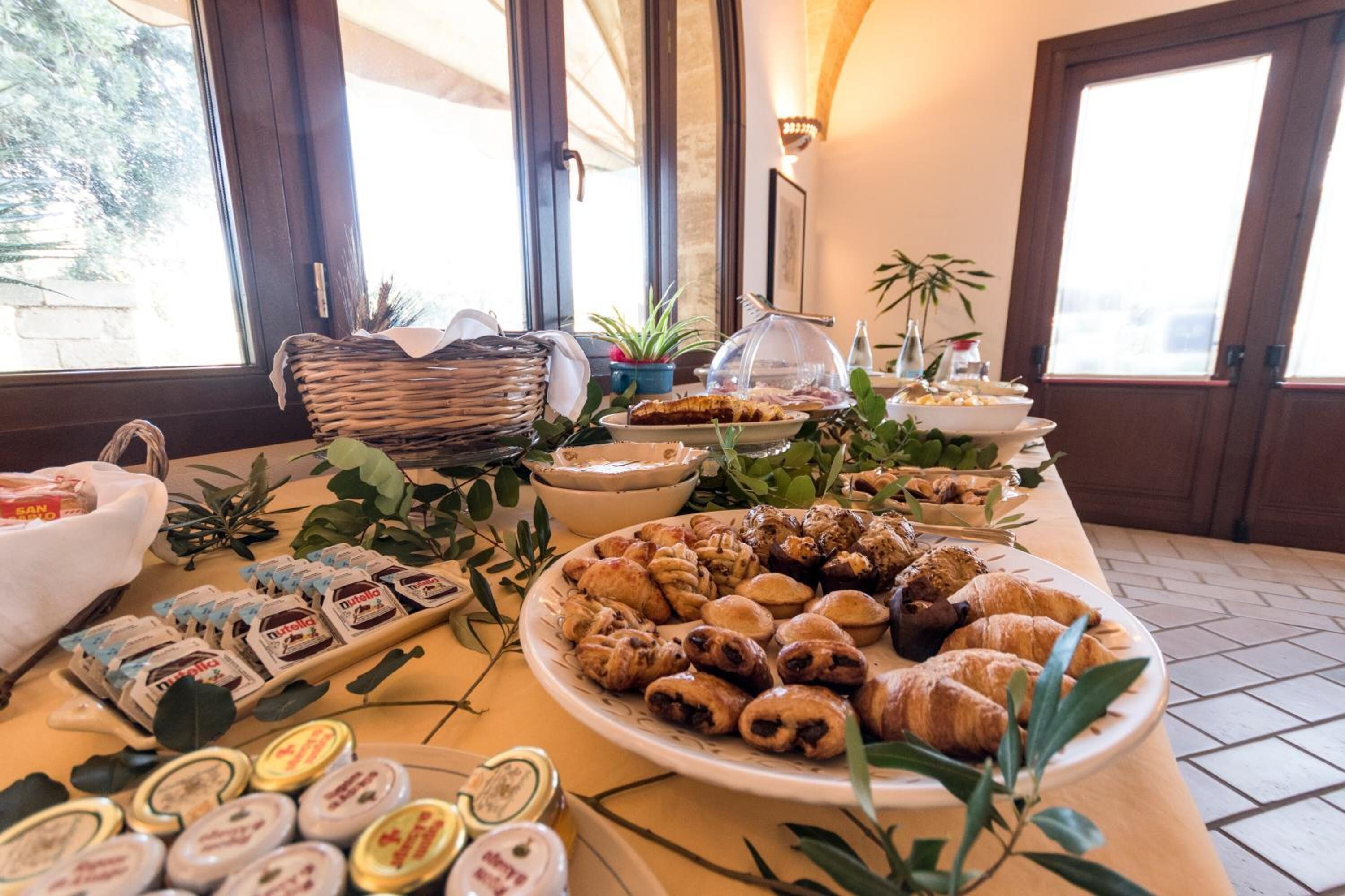 Uma mesa de buffet com diversos pastéis, incluindo croissants e pastéis recheados, além de vários potes de Nutella.