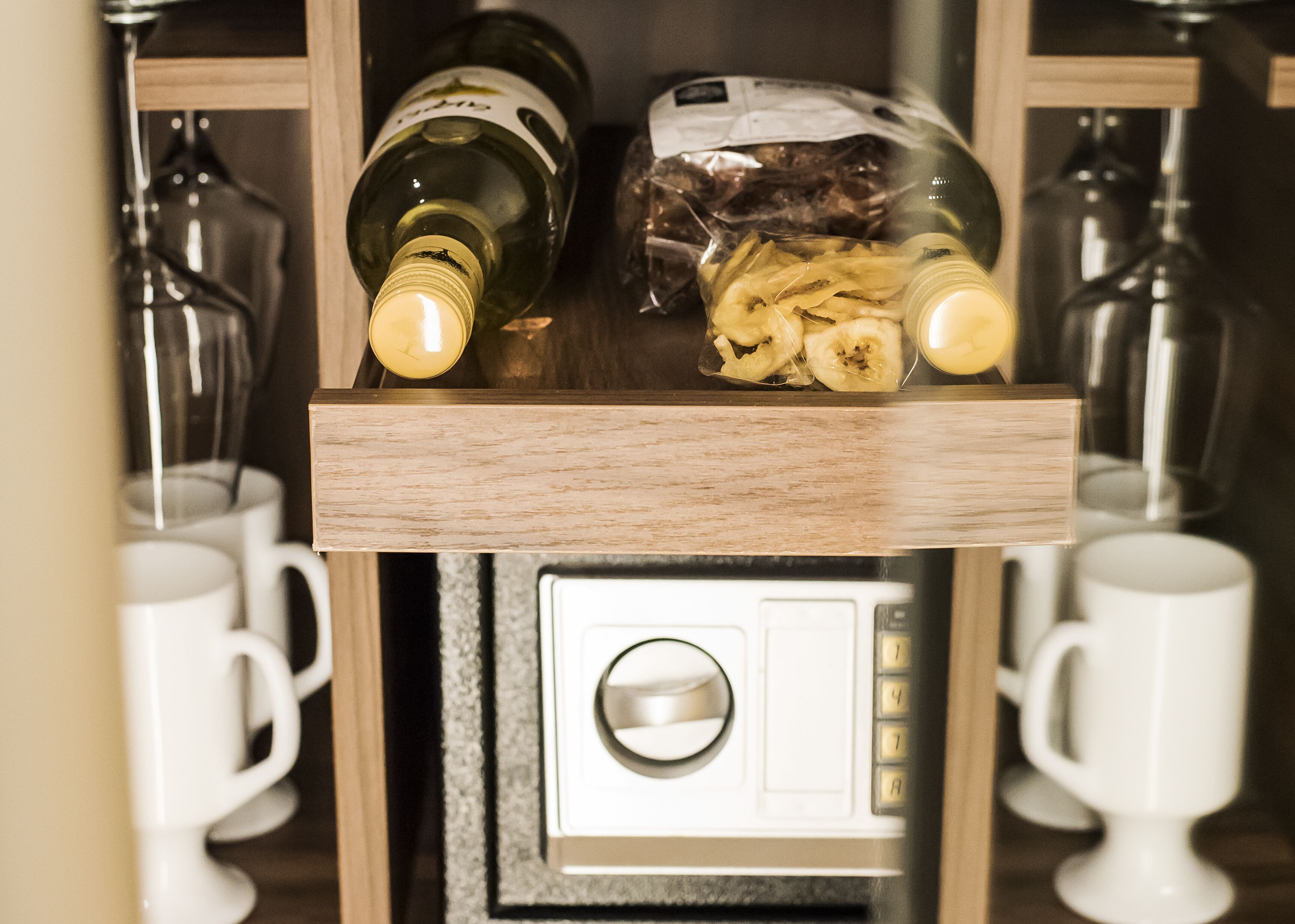 Uma bancada de cozinha com uma máquina de café, uma garrafa de vinho e um saco de petiscos.