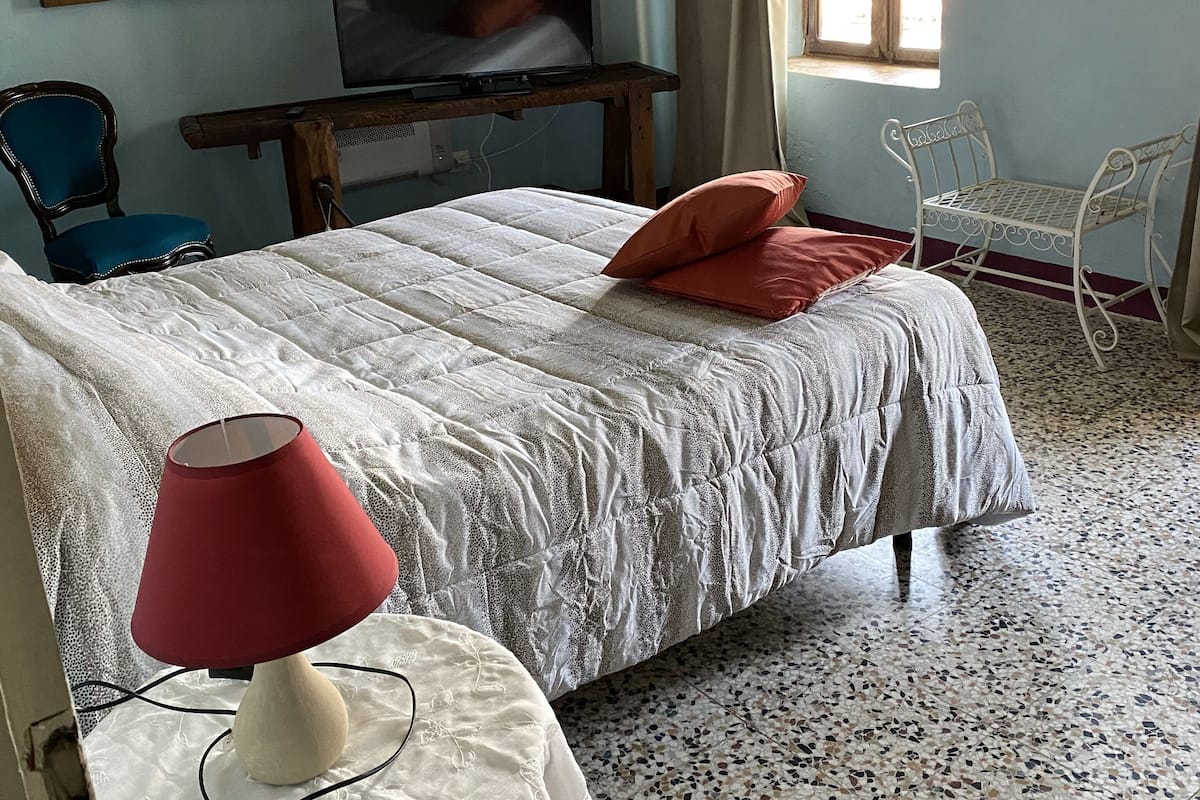 Quarto com cama, televisão, mesa e cadeira.