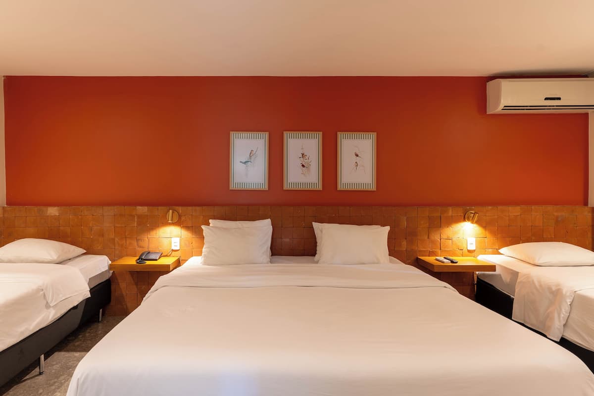 Quarto de hotel com uma cama grande, duas mesas de cabeceira e ar condicionado fixado na parede.