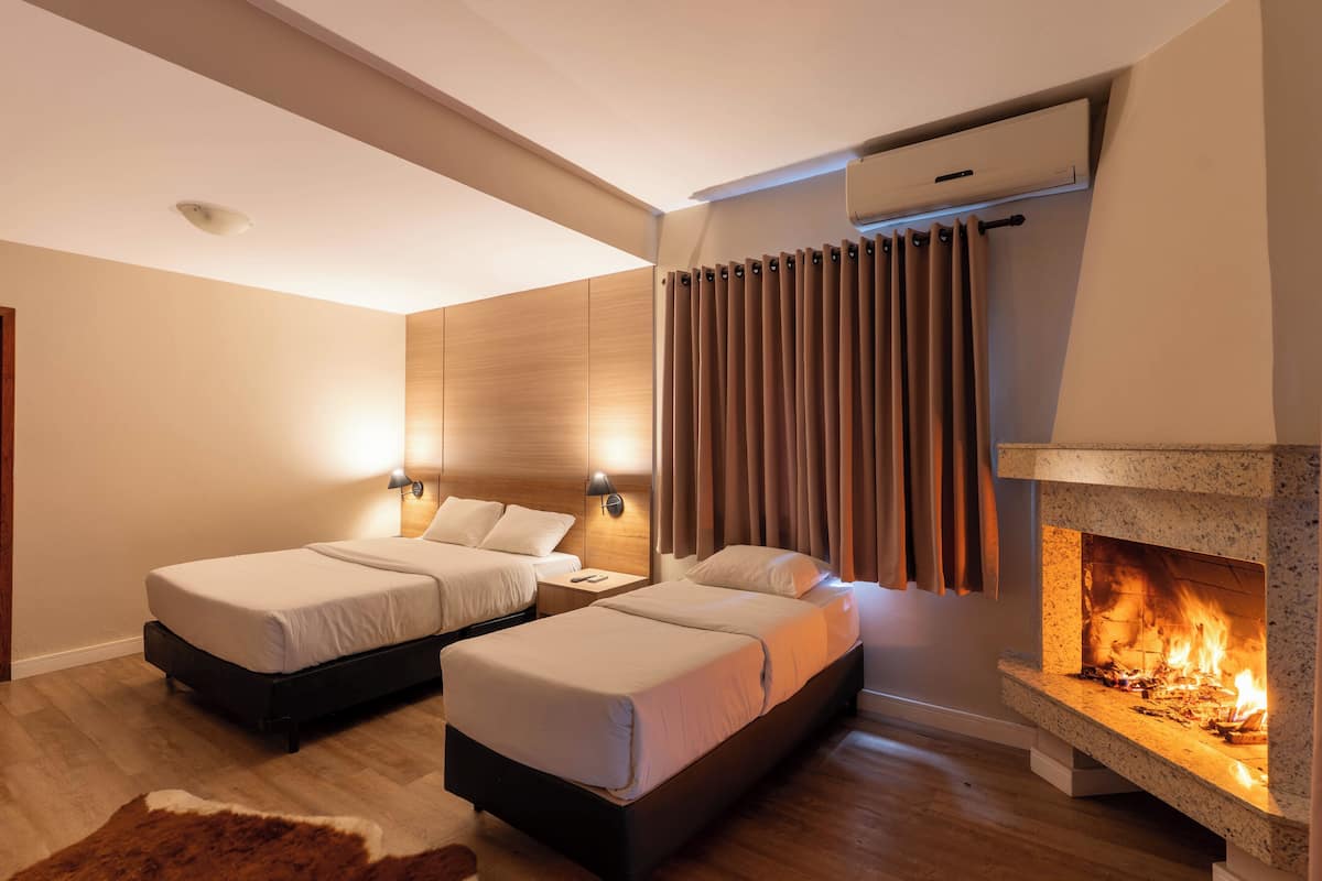Quarto de hotel com duas camas, lareira e design moderno.