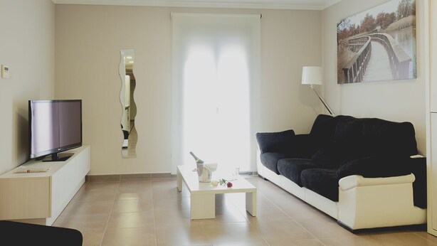 Uma sala de estar moderna com televisão de tela plana, um sofá, uma mesa de centro e um quadro na parede.