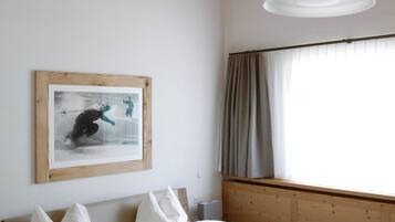 Quarto com cama de madeira, uma obra de arte emoldurada na parede e uma janela com cortinas.