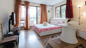 Quarto com cama, escrivaninha, cadeira, luminária e vista para o exterior.
