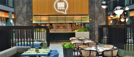 Um espaço de refeições interno com mesas e cadeiras, um letreiro de pizzaria e um design de interiores moderno.