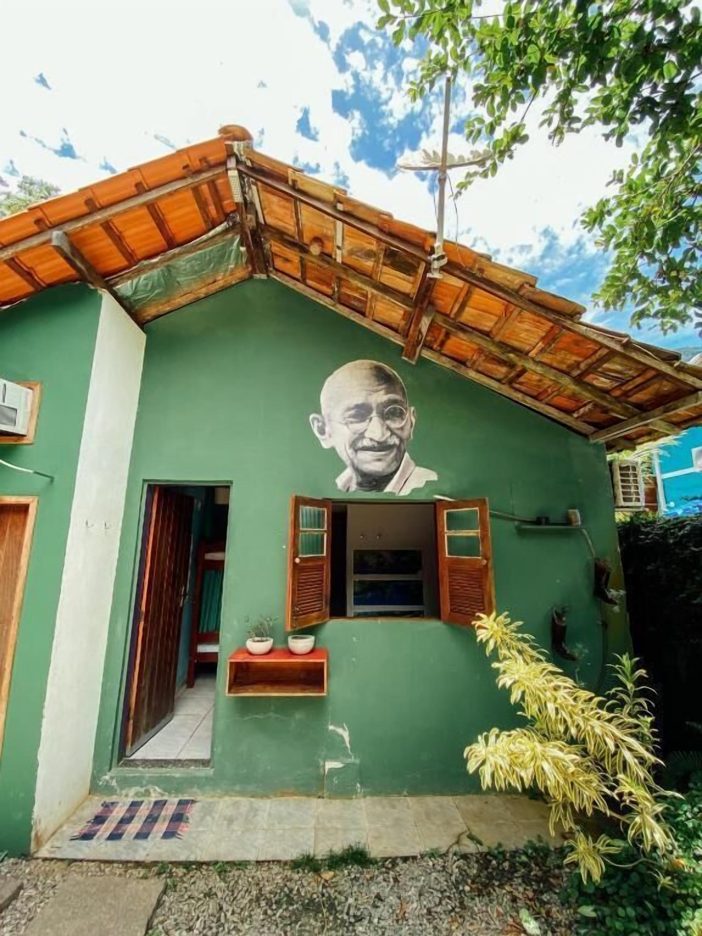 Uma casa com fachada verde, porta de madeira e janelas com persianas de madeira.