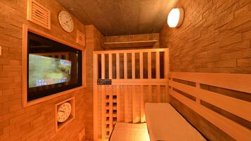 Uma sala de sauna com paredes de madeira, um banco e dois relógios.