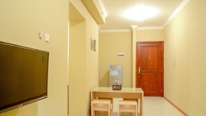 Um corredor com televisão de tela plana na parede, um bebedouro e uma porta de madeira.