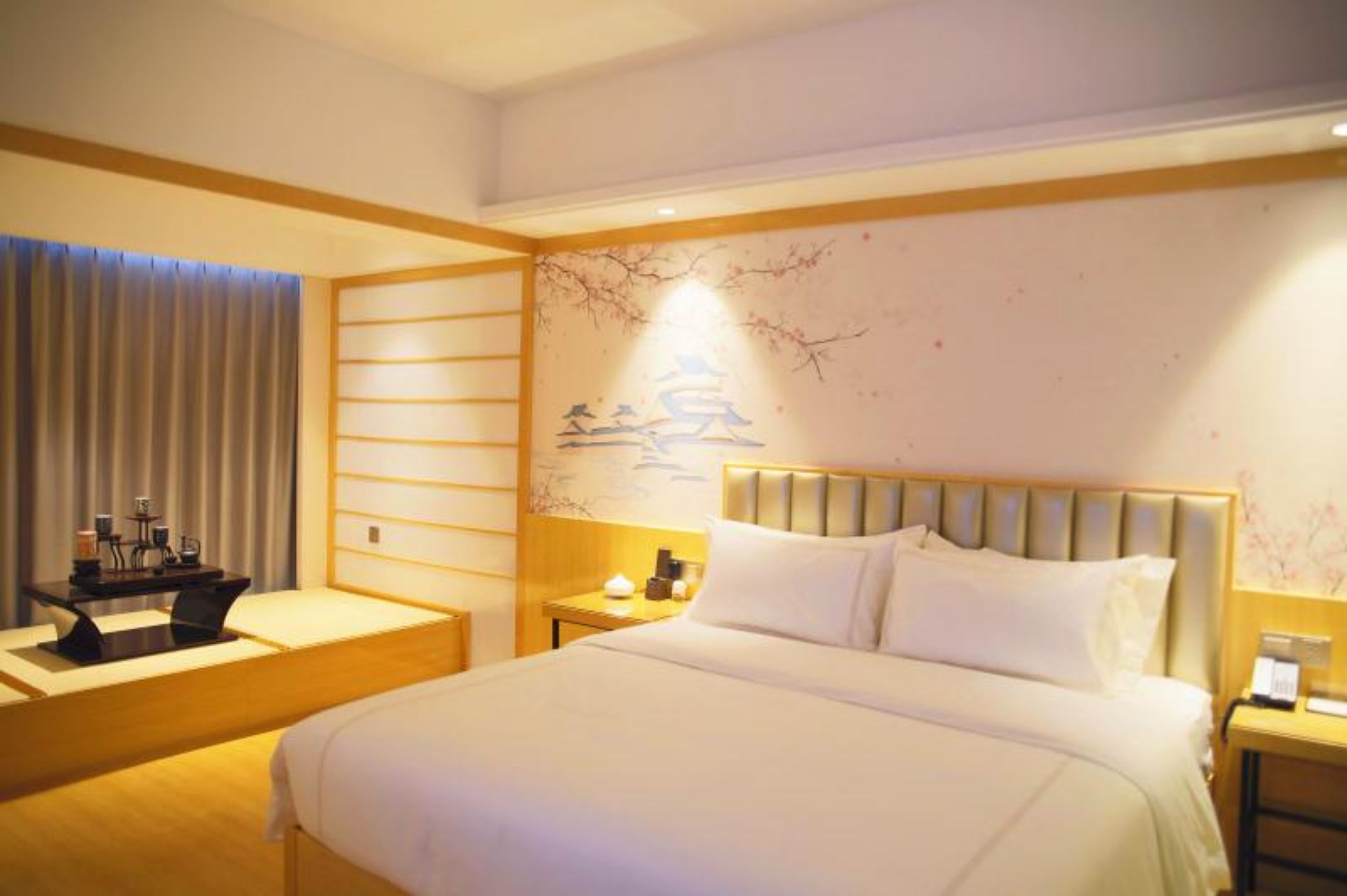 Quarto de hotel com uma cama grande, uma mesa e uma mesinha de cabeceira.