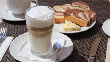 Uma mesa de café da manhã com um copo de leite, uma xícara de café, um prato de pão e uma faca de manteiga.