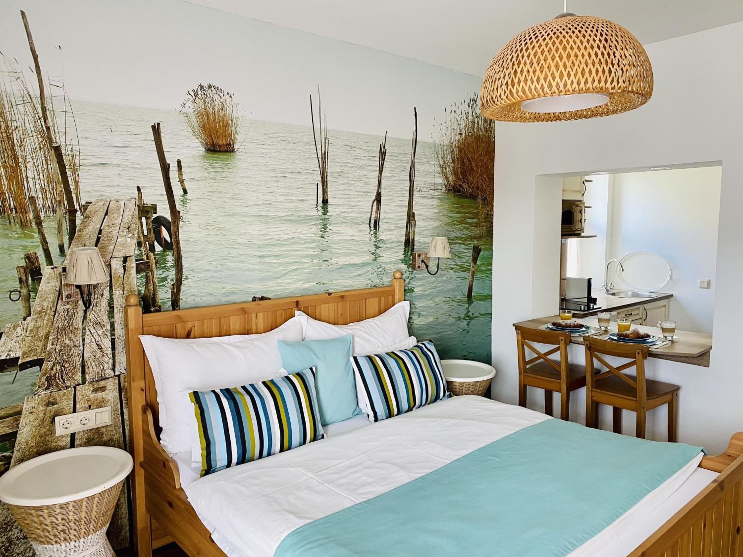 Quarto com cama, mesas de cabeceira, escrivaninha e espelho.