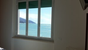 Quarto com janela para um corpo de água e terra distante.