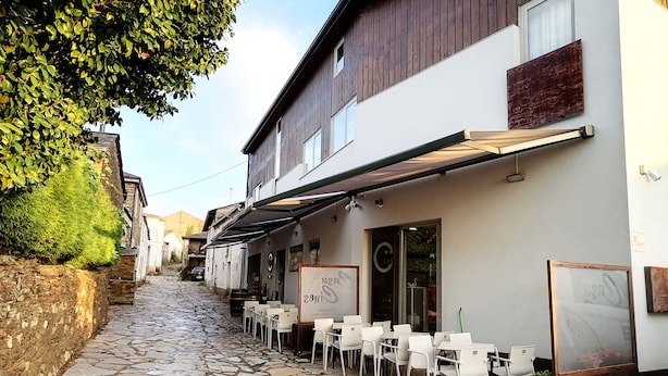 Rua de paralelepípedos com mesas ao ar livre e um edifício com fachada de madeira.