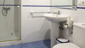 Casa de banho com cabine de duche em vidro, lavatório branco, espelho e sanita.