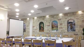 Uma sala de conferências com paredes de pedra, um quadro branco e mesas preparadas para uma reunião.