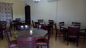 Uma sala de jantar com mesas e cadeiras redondas, um candelabro, ventilador de teto e ar condicionado.
