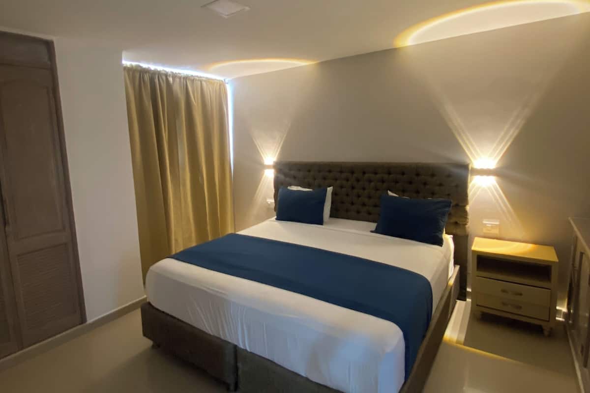 Quarto com cama, mesas de cabeceira e uma porta.