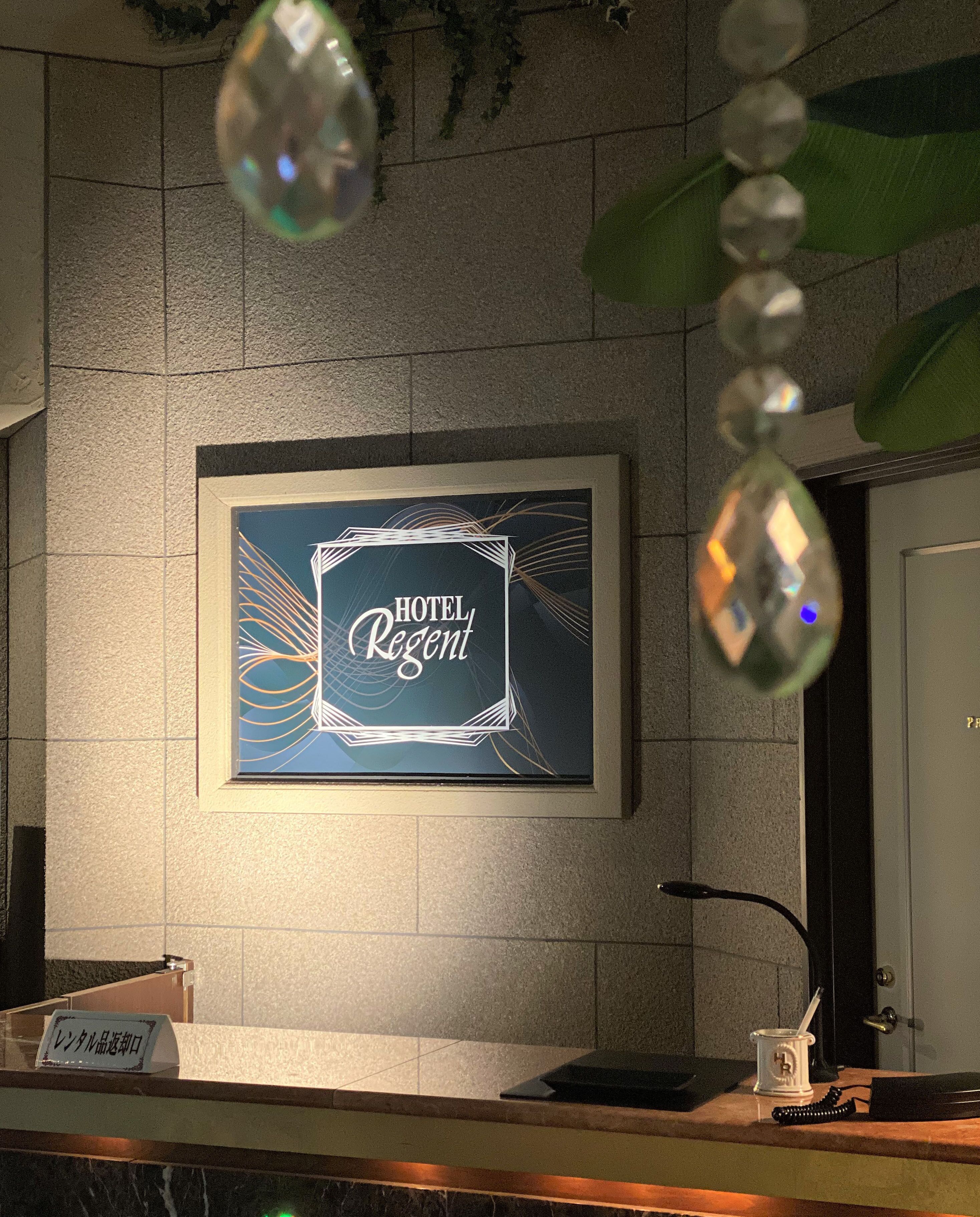 Um quadro com o texto 'HOTEL Recent', uma receção, uma porta e elementos decorativos pendurados.