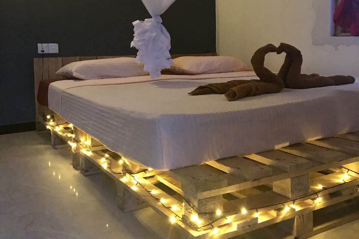 Uma cama com dossel, toalhas em formato de coração e luzinhas.