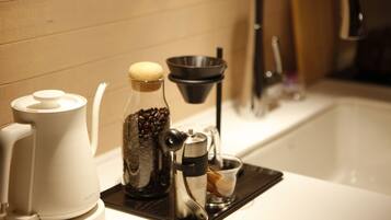 Uma cafeteira, um moedor e uma xícara sobre um tabuleiro.