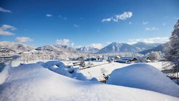 Paisagem coberta de neve com casas e montanhas ao fundo.