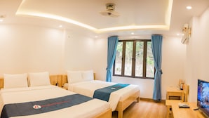 Quarto de hotel com duas camas, uma televisão, uma mesinha e uma janela com cortinas.
