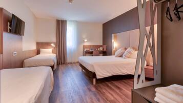 Quarto de hotel com duas camas, televisão, secretária e espelho de casa de banho.