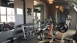 Uma academia com diversos equipamentos de exercício, incluindo halteres, bancos e máquinas de musculação.