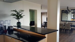 Cozinha moderna com bancada preta, armários de madeira e um vaso de planta.