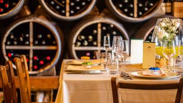 Um restaurante com mesa posta para refeição, copos de vinho e um menu.