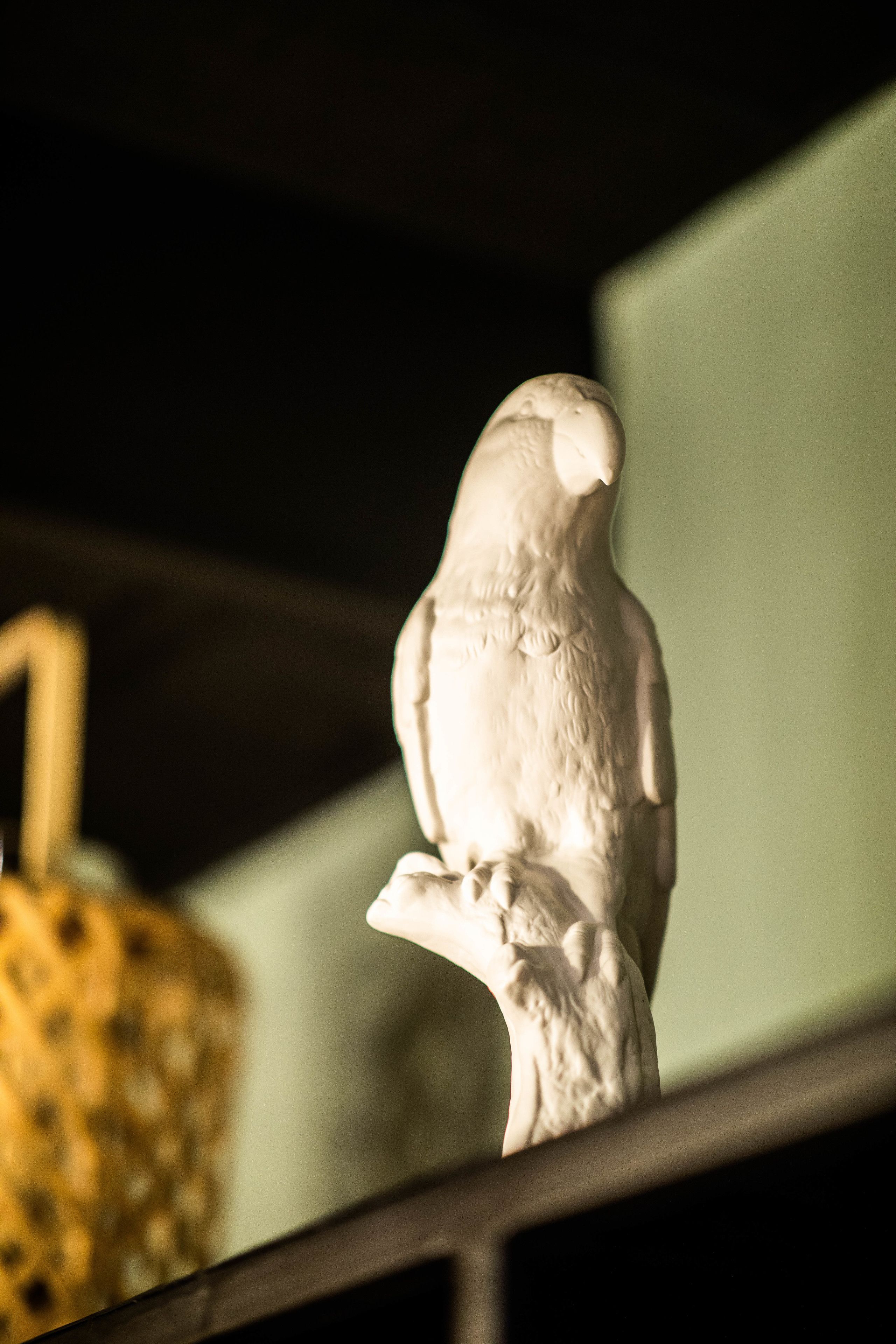 Uma escultura de pássaro branco sobre um suporte.