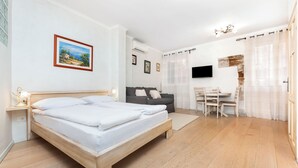 Quarto com cama de madeira, sofá, televisão e área de refeições.
