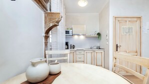 Uma cozinha compacta com armários brancos, micro-ondas e uma porta de madeira com um mapa.