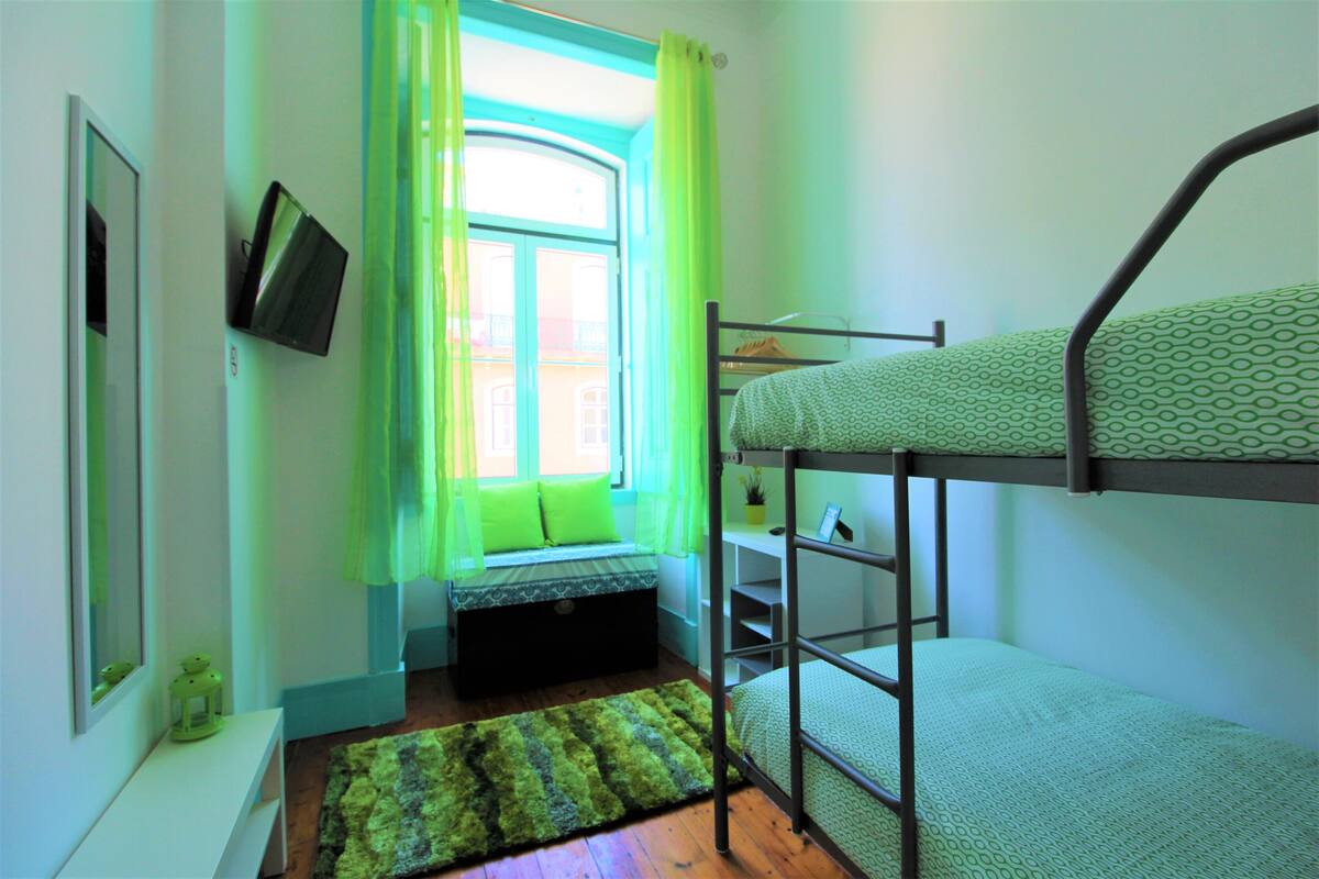 Quarto com beliche, janela, espelho e prateleira pequena.