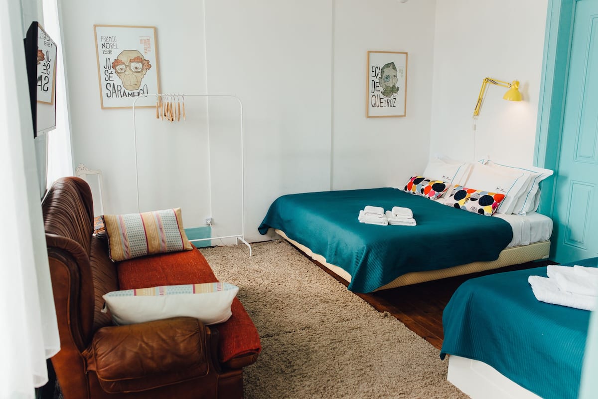 Um quarto aconchegante com duas camas, um sofá de couro marrom e um abajur.