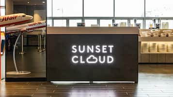 Uma mesa de recepção com um letreiro de neon que diz "Sunset Cloud" e um modelo de avião em exposição.