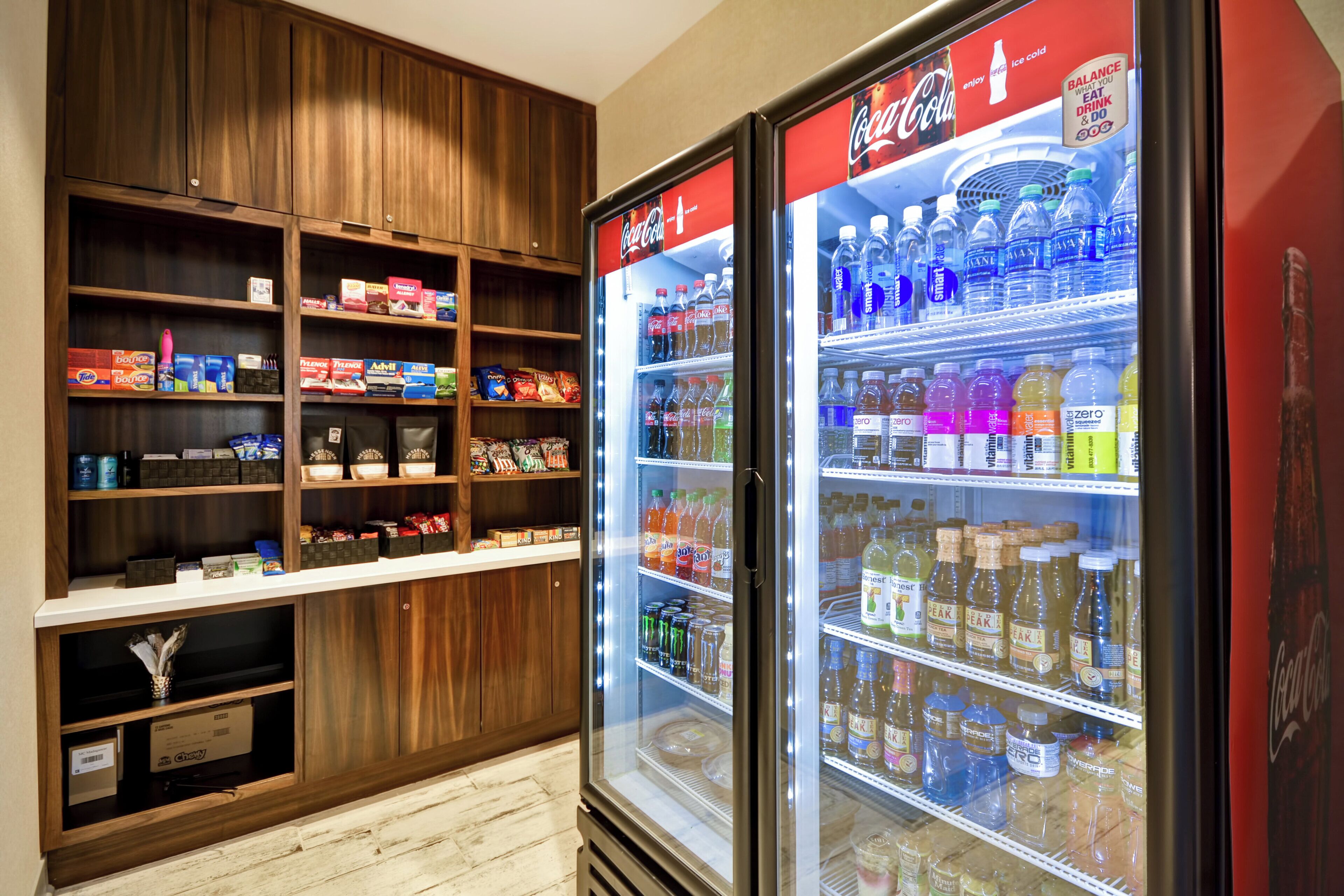 Uma área de máquinas de venda automática com lanches, bebidas e um refrigerador Coca-Cola.