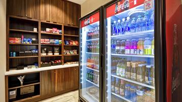 Uma área de máquinas de venda automática com lanches, bebidas e um refrigerador Coca-Cola.