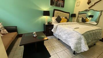 Quarto de hotel com cama, mesa de cabeceira, mesa, cadeira e espelho.